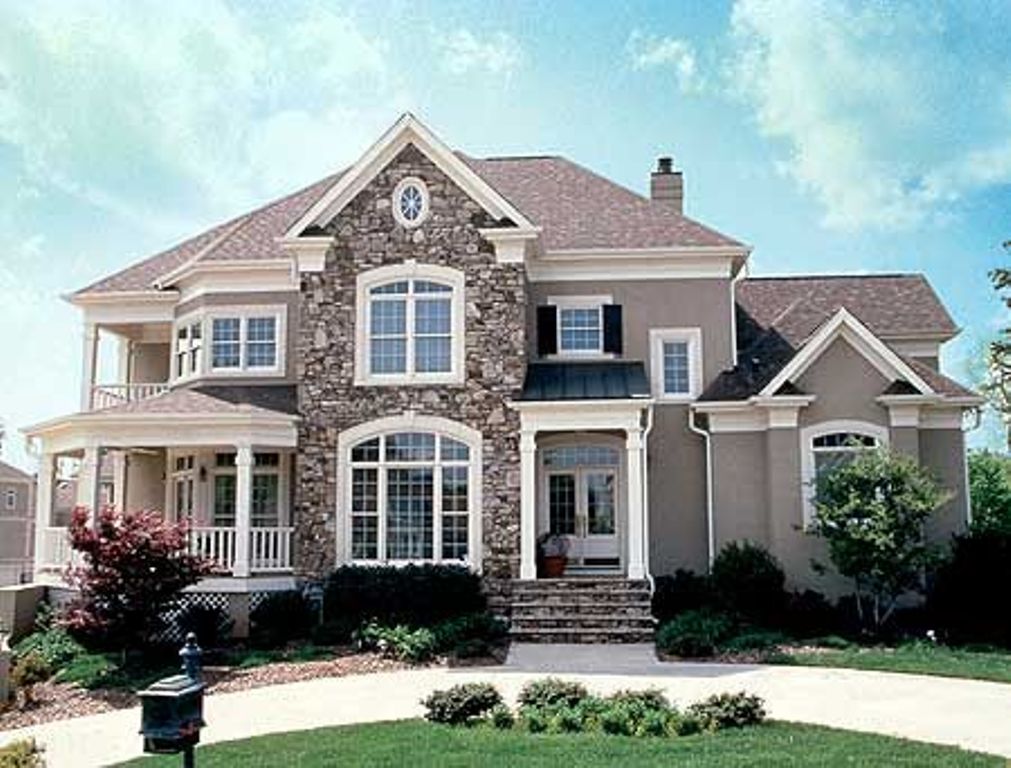 A large, two-story house with light beige and stone exterior, multiple ...