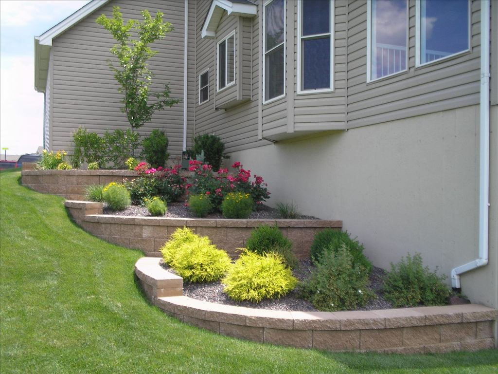 A side view of a house with beige vinyl siding features a landscaped ...